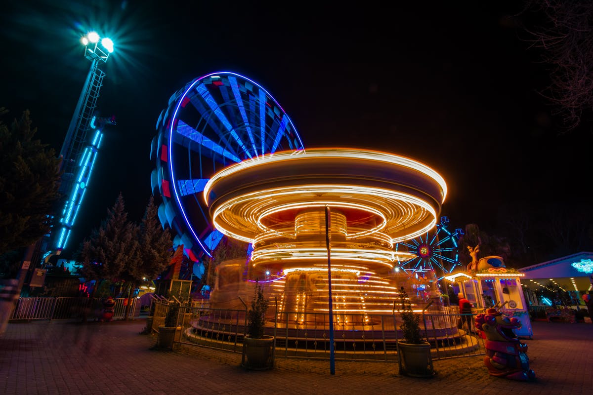 Colorful carousel and ferris wheel illuminated at night at a theme park