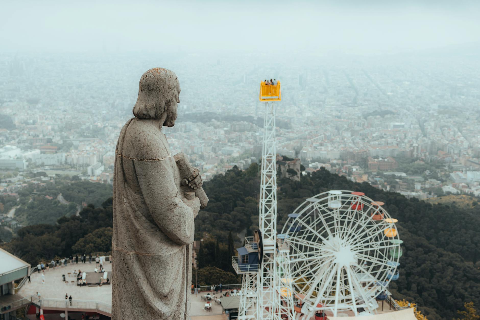Statue overlooking Barcelona cityscape with Tibidabo amusement park and Ferris wheel