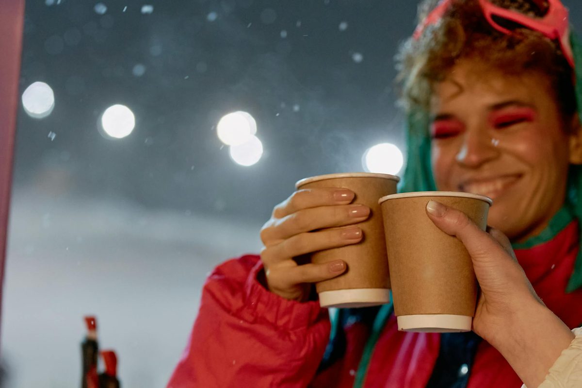 Two people toasting with beverages during a winter night