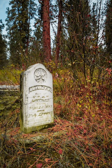 Old tombstone surrounded by bright autumn leaves in orange and yellow