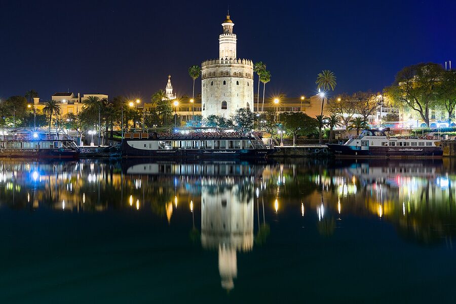 Torre del Oro tower illuminated at night beside the Guadalquivir River in Seville