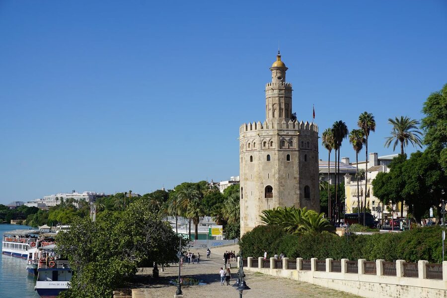 The golden Torre del Oro tower beside the Guadalquivir River on a sunny day in Seville
