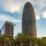 Torre Glories tower in Barcelona with distinctive bullet-shaped design against blue sky