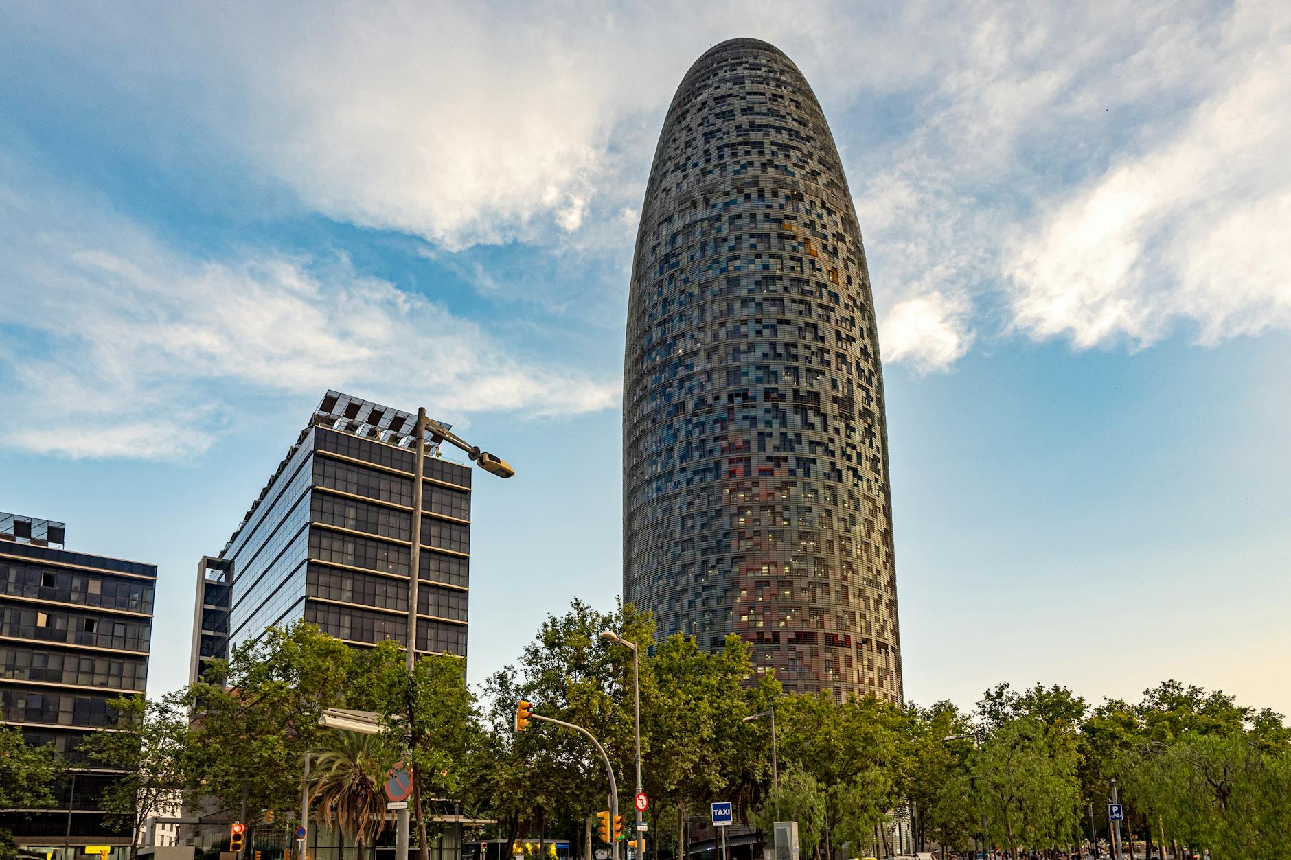 Torre Glories tower in Barcelona with distinctive bullet-shaped design against blue sky