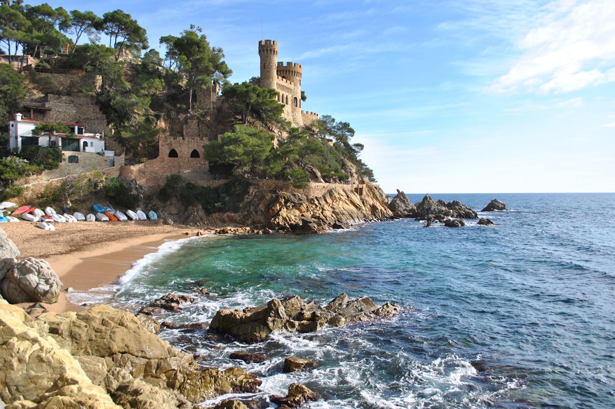 Medieval castle perched on rocky cliffs overlooking bright blue sea