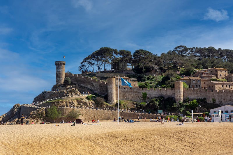 Historic castle of Tossa de Mar overlooking a sandy beach and blue Mediterranean sea