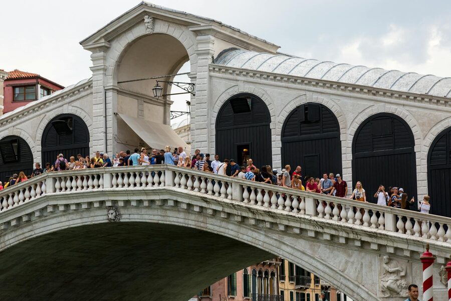 Rialto Bridge over the Grand Canal in Venice with travelers on a sunny day