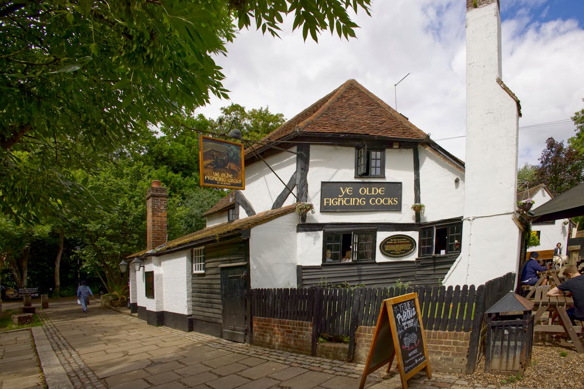 Historic English pub exterior with hanging flower baskets and traditional signage