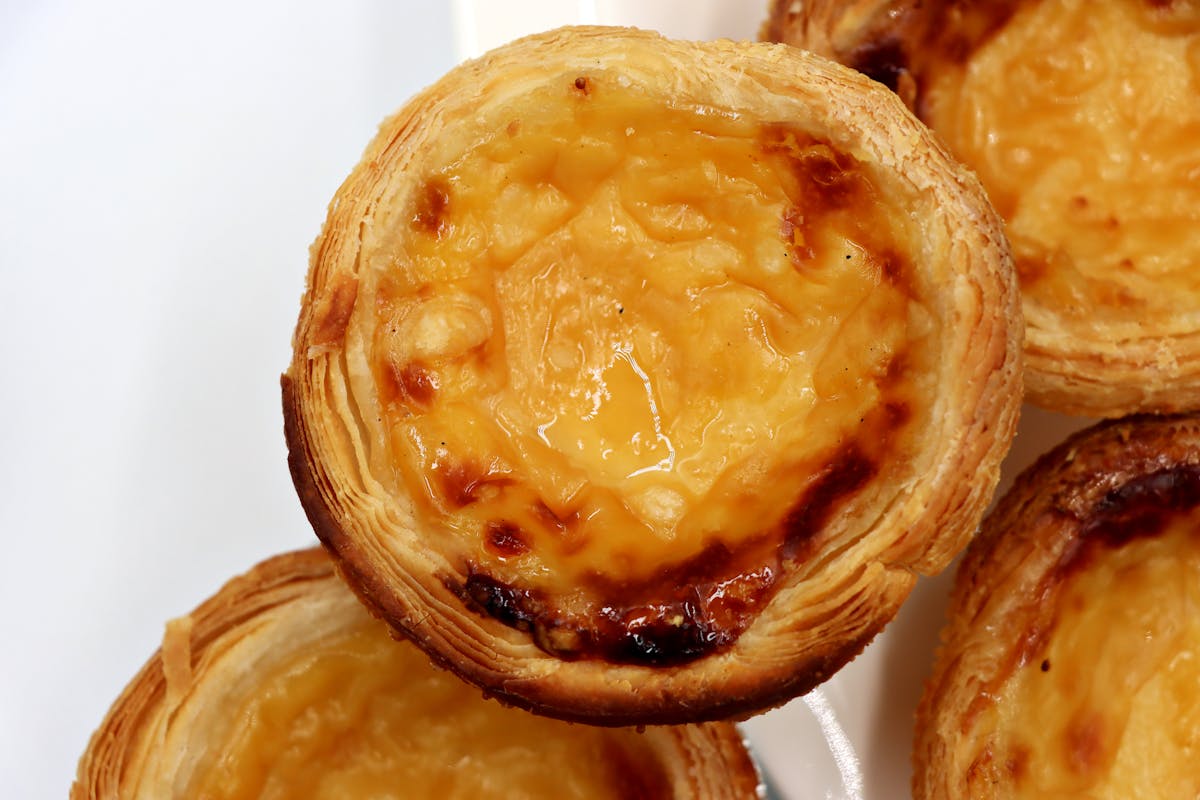 Freshly baked Portuguese custard tarts with caramelized tops on a tray