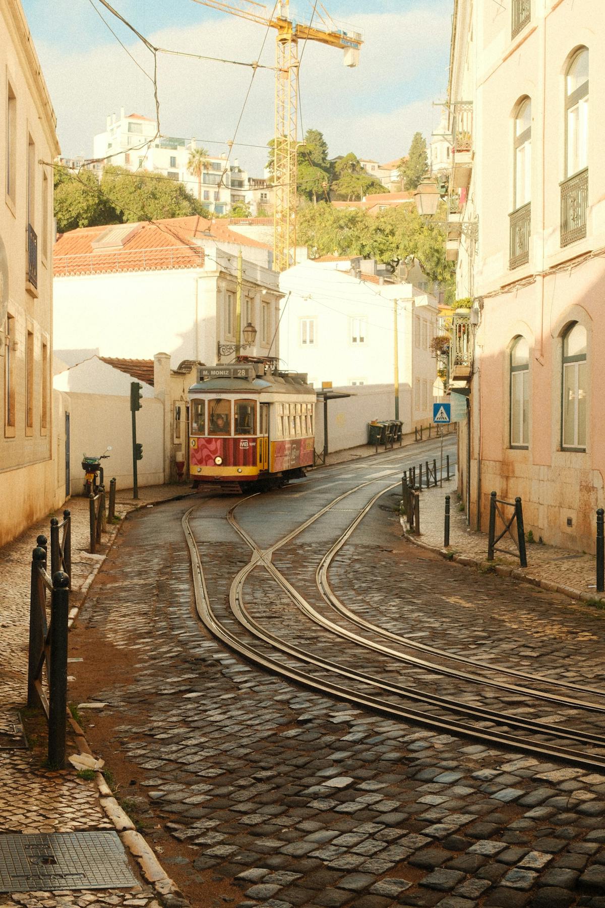 Traditional yellow tram turning a sharp corner on narrow cobblestone tracks in Lisbon