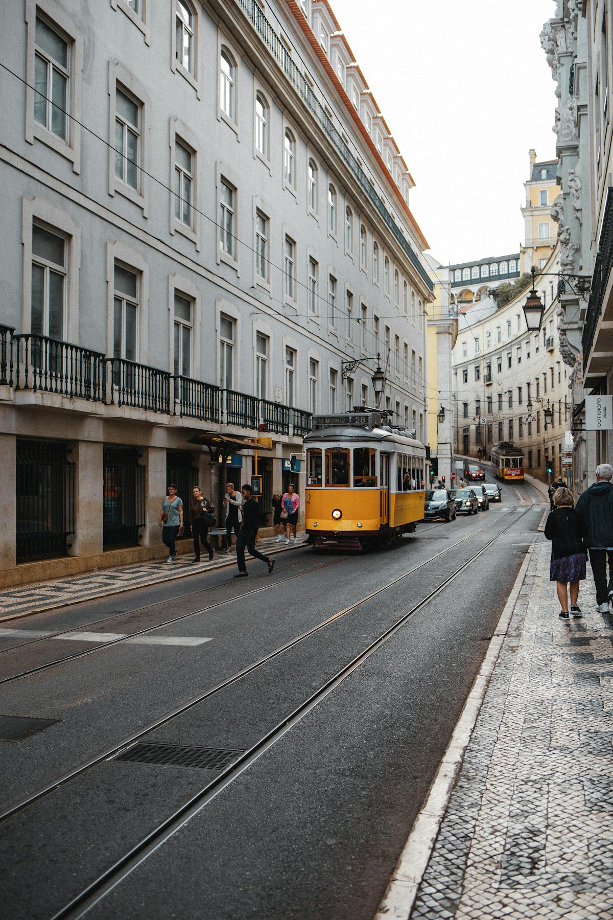 Lisbon yellow trams passing through lively narrow streets