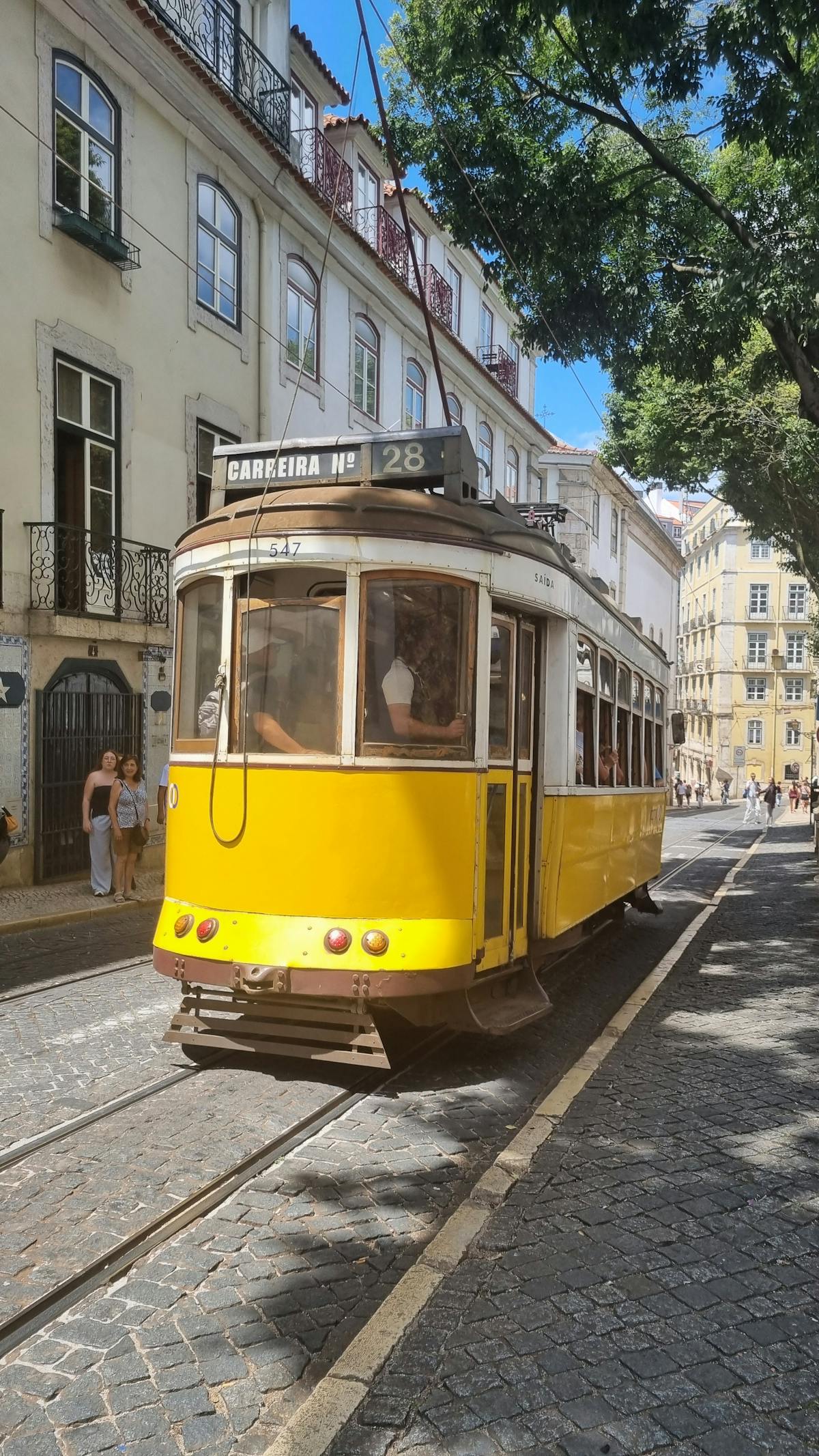 Iconic yellow tram on a bright Lisbon summer day with clear blue skies