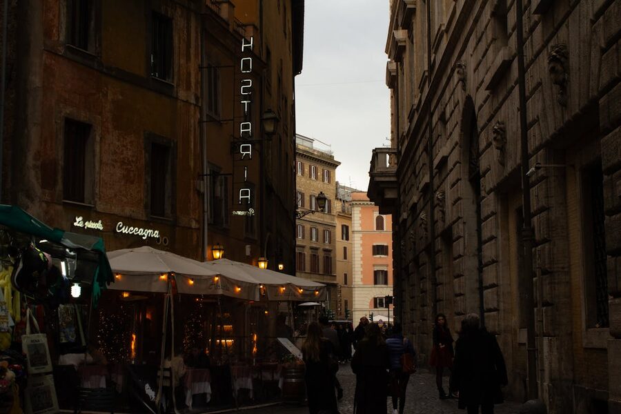 A cozy street in Rome with restaurants and diners at evening time