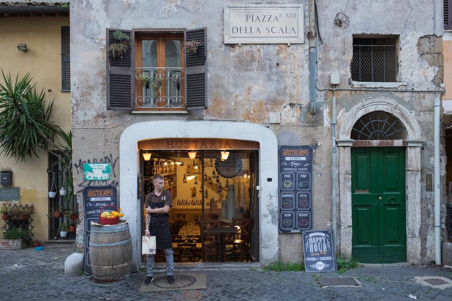 A charming restaurant entrance with wooden doors and warm lighting in Trastevere, Rome
