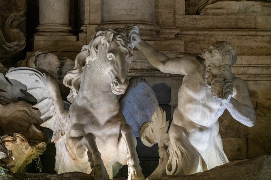 Baroque sculptures of the Trevi Fountain lit up dramatically at night