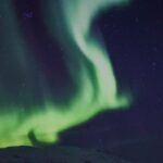 Green aurora borealis dancing over Tromso Norway at night