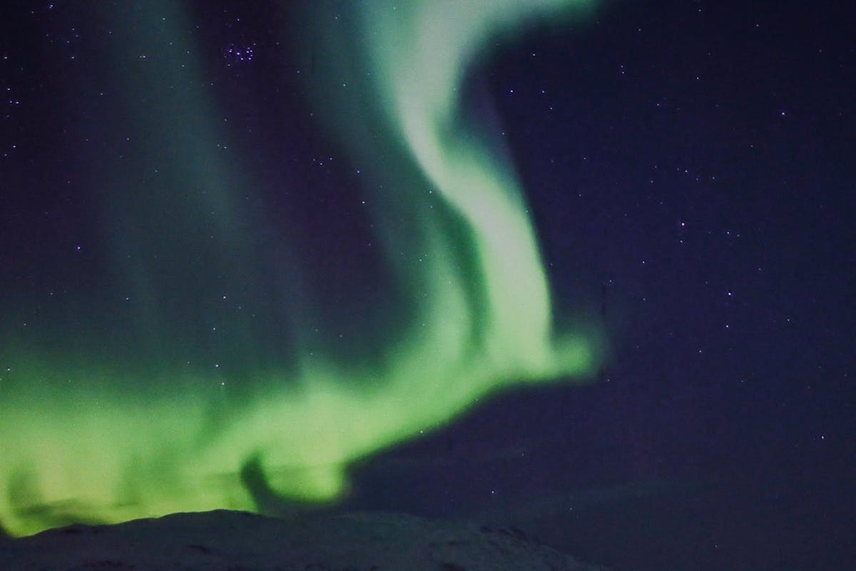Green aurora borealis dancing over Tromso Norway at night