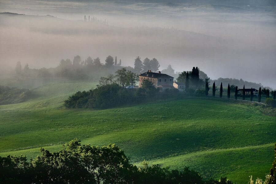A Tuscan farmhouse surrounded by misty rolling hills in the countryside outside Florence