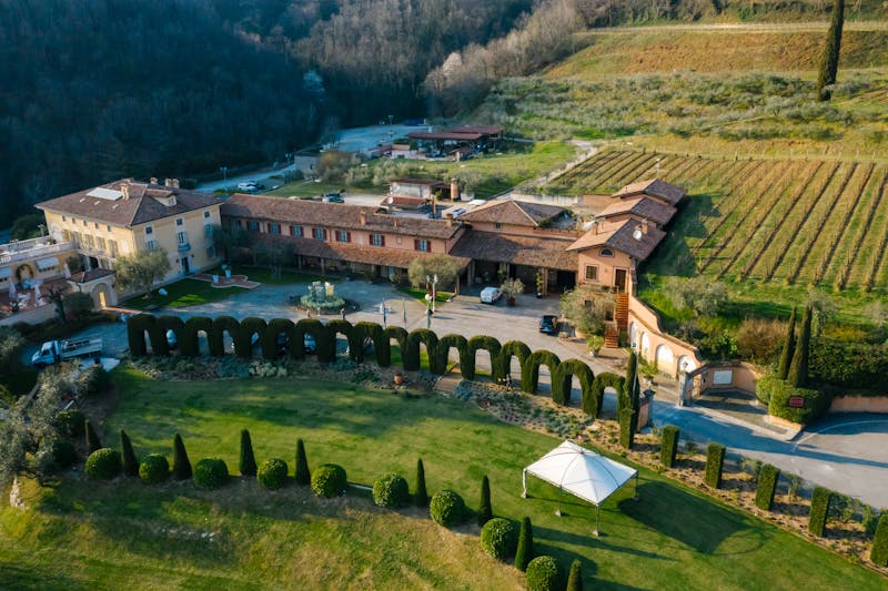 Aerial photograph of a grand Tuscan vineyard estate surrounded by gardens and rolling hills