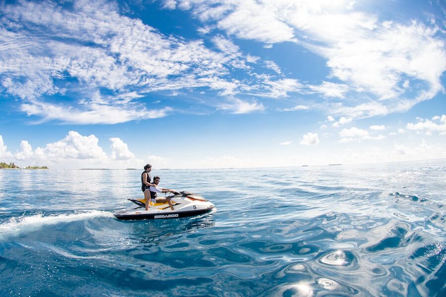 Two people riding on a jet ski over blue ocean water