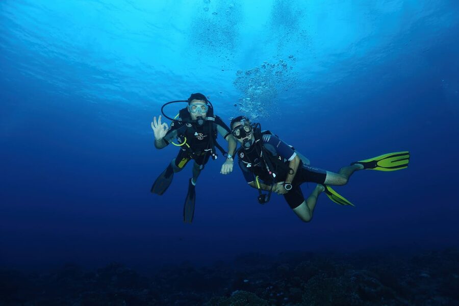 Two scuba divers with gear exploring the deep blue ocean