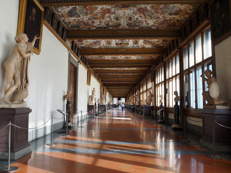 Long corridor inside the Uffizi Gallery with statues and artwork on display