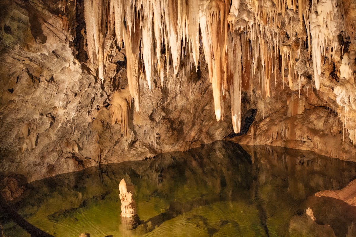 Underground lake with stalactites reflecting in still water inside a cave