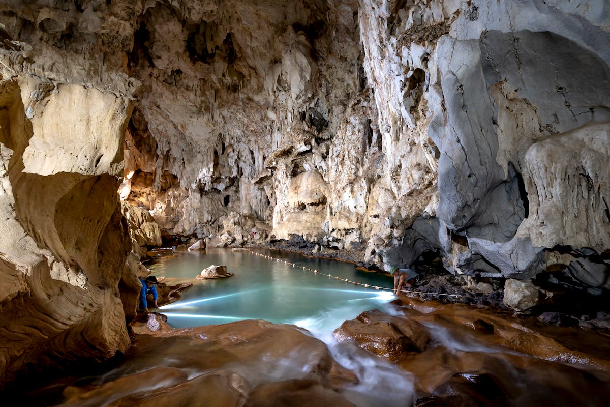 Crystal clear underground lake inside a limestone cave with stalactite formations above