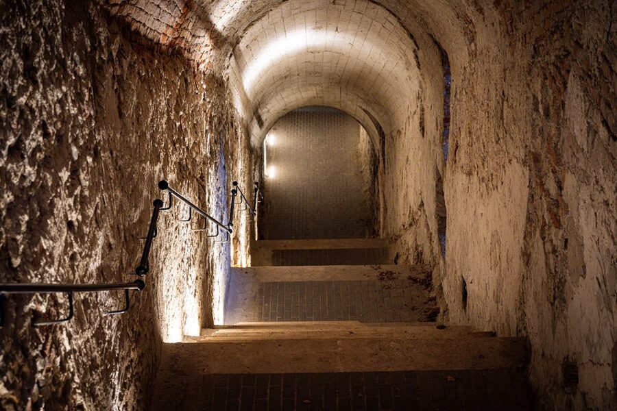 Dimly lit stone staircase leading down into an underground passage