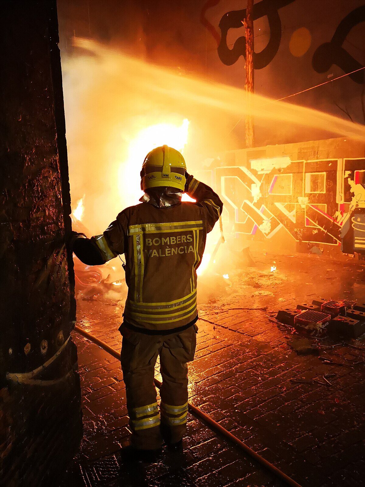 Firefighter watching a burning falla sculpture during La Crema in Valencia