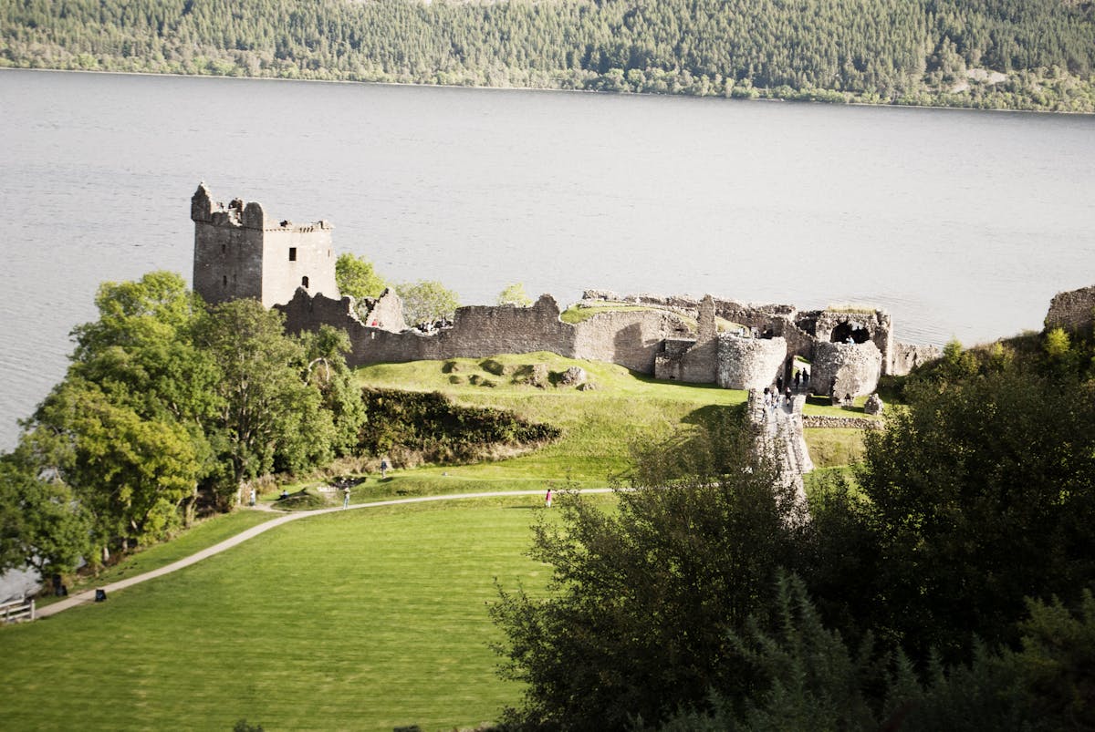 The stone ruins of Urquhart Castle sitting on a promontory overlooking the deep waters of Loch Ness in Scotland