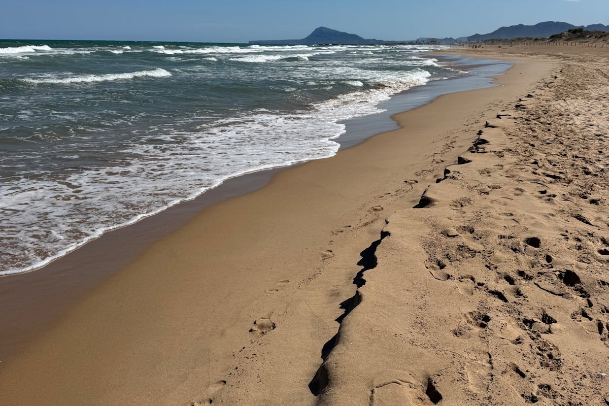 Sandy beach with gentle waves under a clear blue sky near Valencia