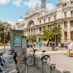 City street in Valencia, Spain with bicycles for rent near a historic building.