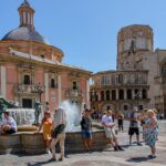 Tourists enjoying a sunny day at Plaza de la Virgen in Valencia with the cathedral in the background