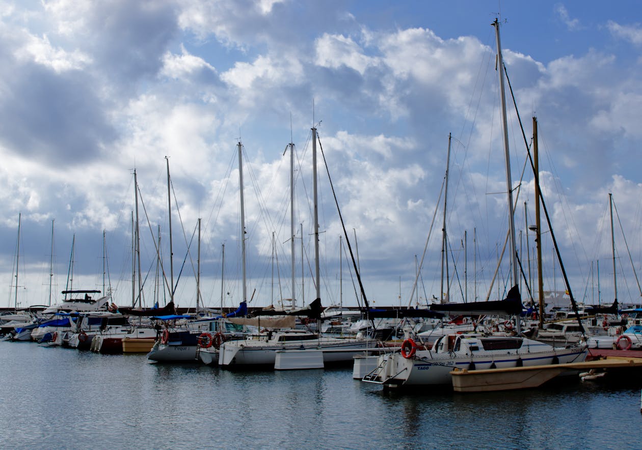 Sailboats moored at a marina in Valencia Spain under a cloudy Mediterranean sky
