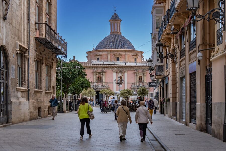 People walking along a charming narrow street in Valencia old town with colorful historic buildings