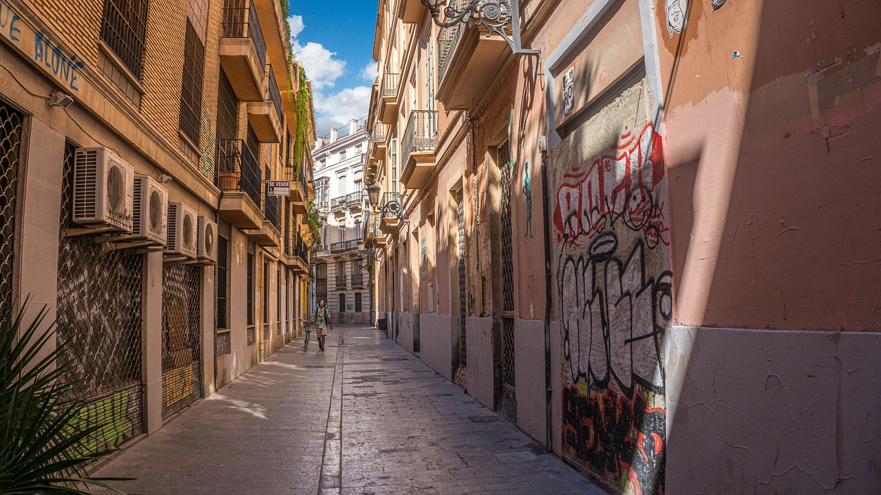 Narrow old town alley in Valencia with traditional colorful buildings and blue sky