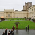 Visitors walking through the Vatican Museums courtyard on a cloudy day in Rome