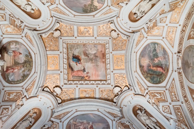 Richly decorated ceiling with gold detailing and frescoes in a Vatican Museum corridor