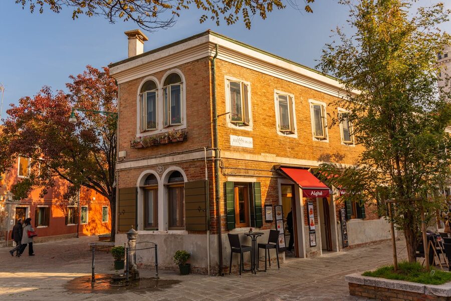 A warm sunlit cafe on a Venice street corner with colorful buildings