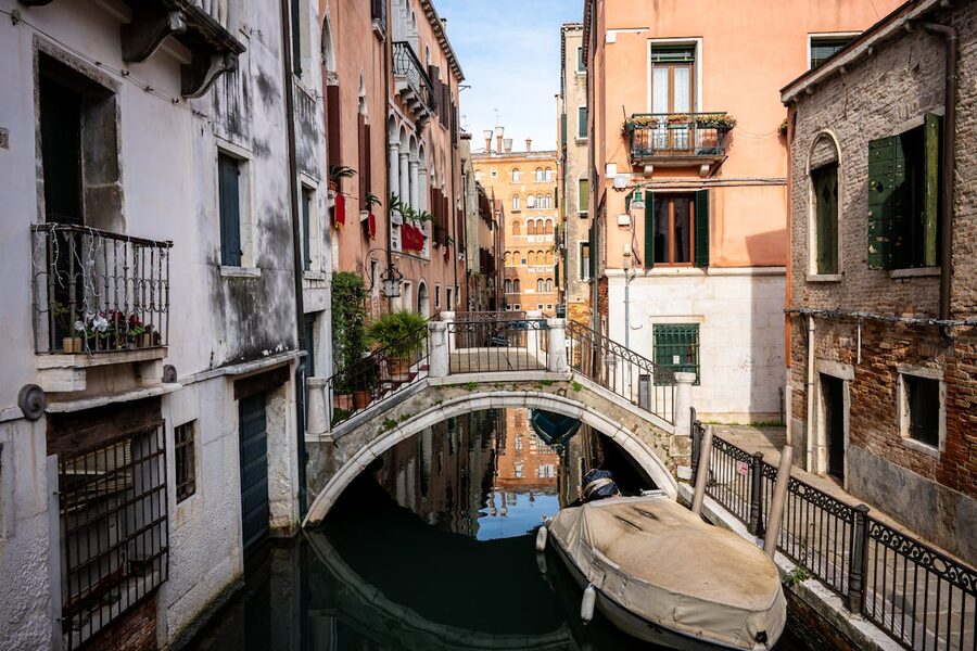 A small bridge over a narrow Venice canal with a moored boat
