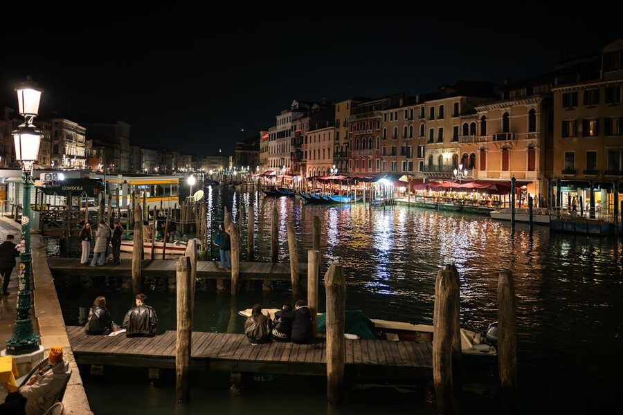A Venice canal at night with warm lights reflecting on the water