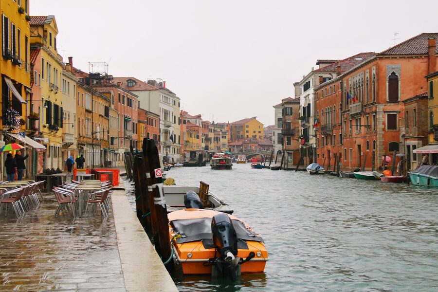 A quiet Venice canal with empty cafe tables and colorful facades