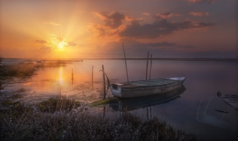 A boat crossing the calm waters of the Venice lagoon with islands visible in the distance