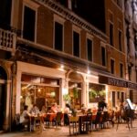 Diners enjoying an evening meal at a canalside restaurant in Venice