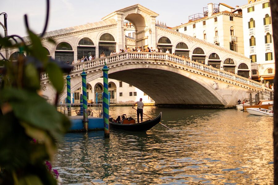 The Rialto Bridge illuminated by sunset light with a gondola on the Grand Canal