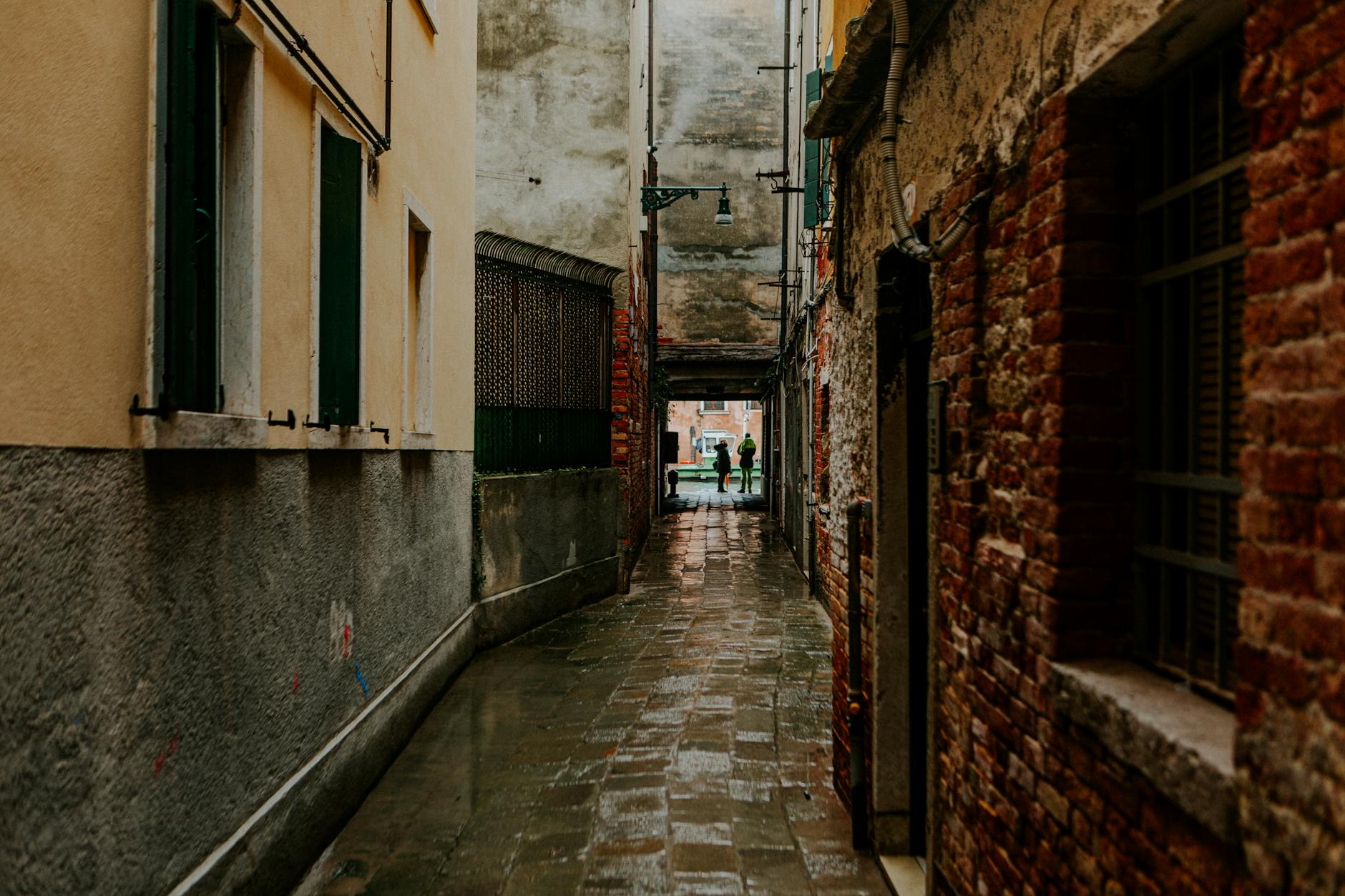 Rustic alleyway in Venice with wet cobblestones and colorful architecture