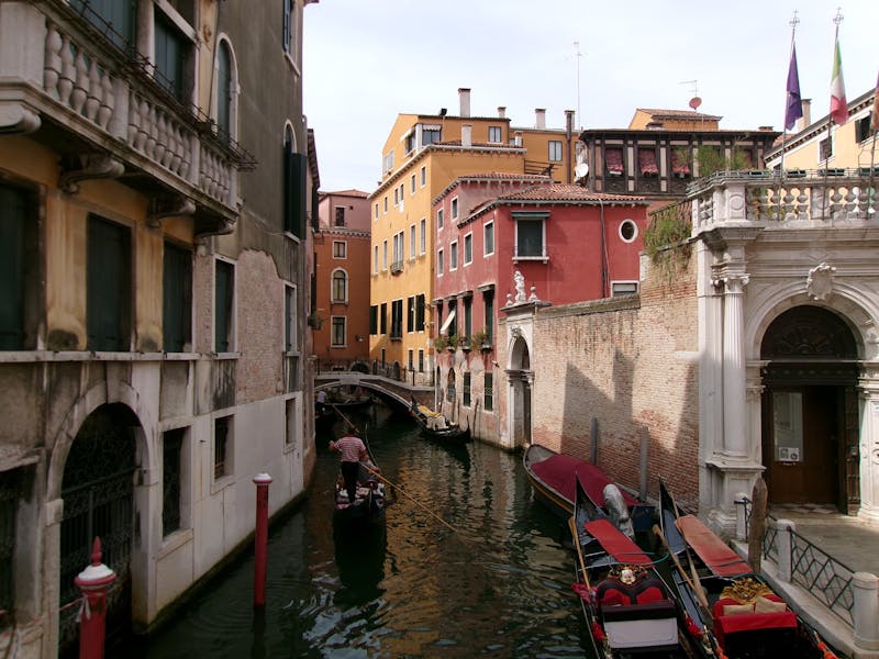 Gondola navigating a narrow Venice canal surrounded by colorful buildings