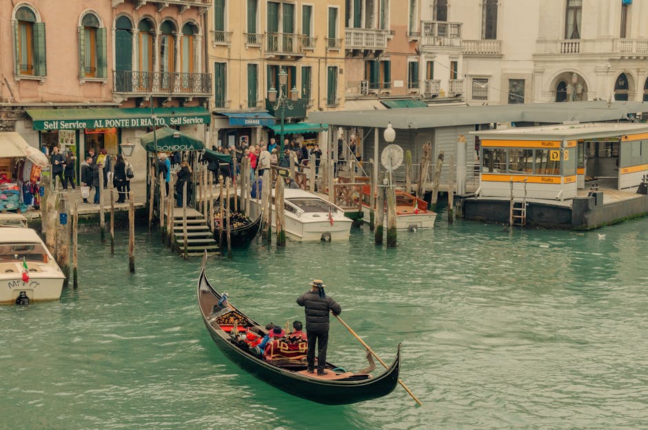 A gondolier steering his gondola along a narrow Venice canal with historic buildings on both sides