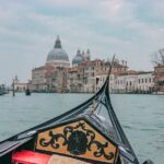 A gondola gliding along the Grand Canal in Venice with historic buildings and a basilica in the background